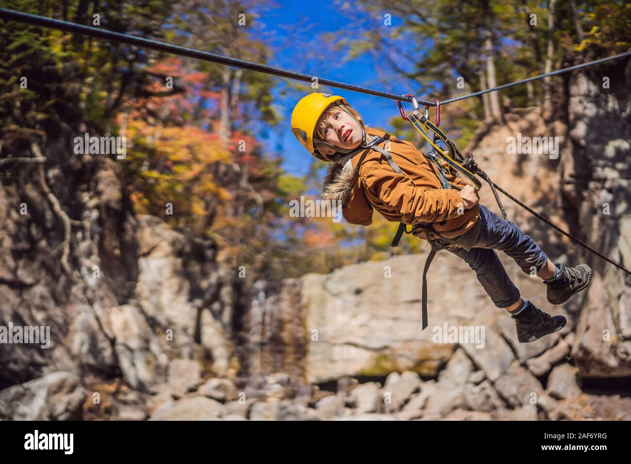 Brave little boy rappelling high among the trees in an Adventure Park ...