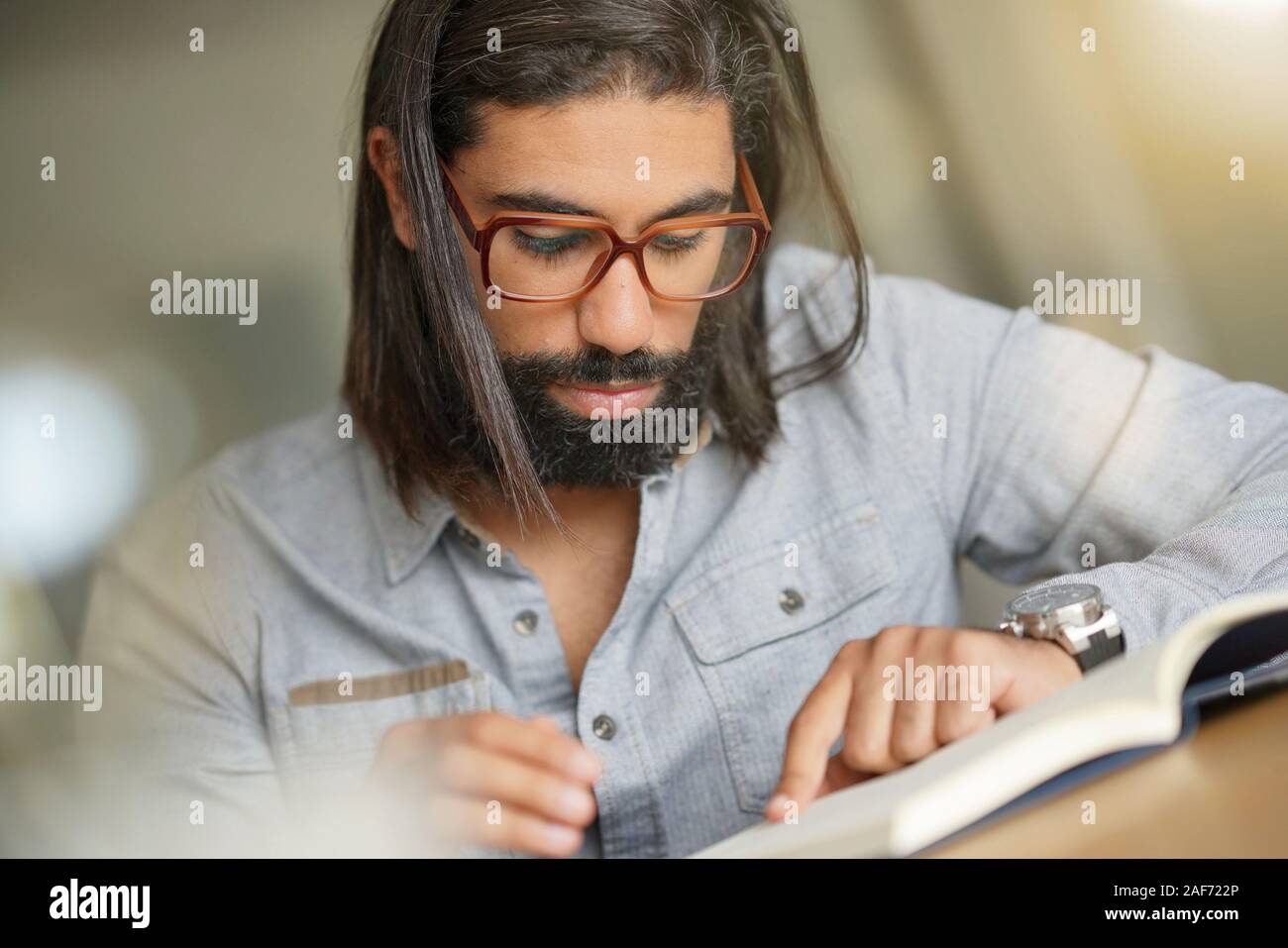 Dark-haired man with eyeglasses reading book Stock Photo - Alamy