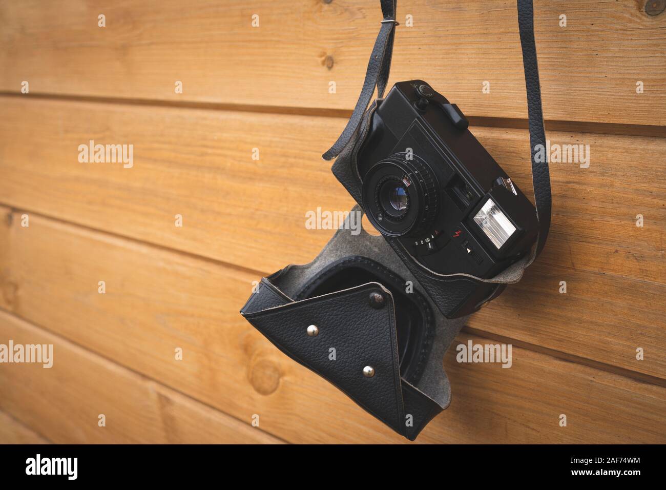 Old fashioned photo camera hanging on wood wall Stock Photo - Alamy