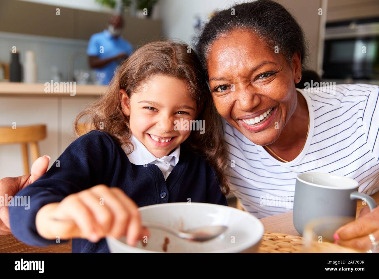 Portrait Of Grandparents In Kitchen With Granddaughter Eating Breakfast ...