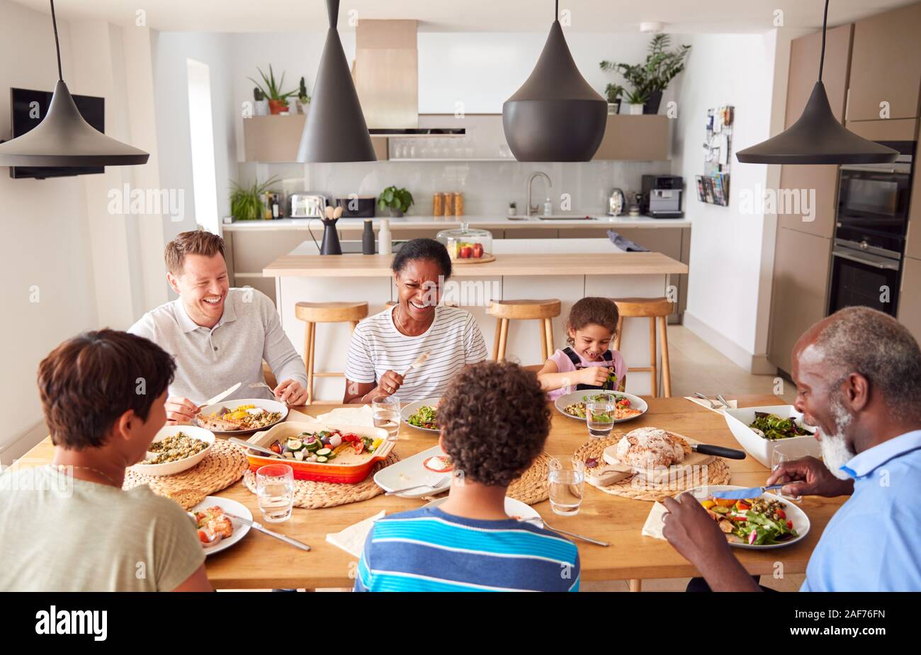 Multi-Generation Mixed Race Family Eating Meal Around Table At Home ...