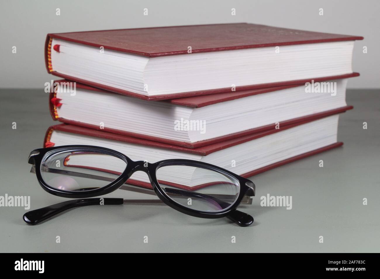 Heap of three red books and black glasses Stock Photo - Alamy