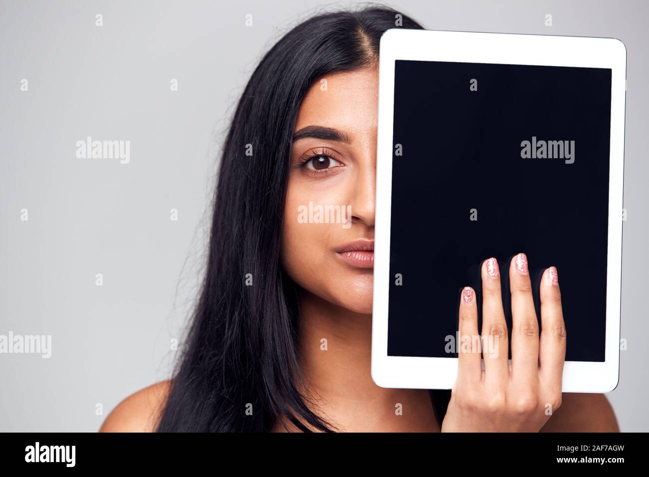 Studio Portrait Of Serious Young Woman Covering Face With Digital ...