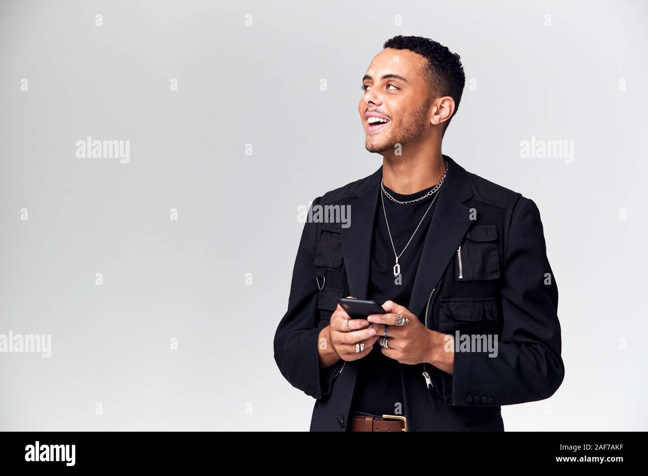 Studio Shot Of Causally Dressed Young Man Using Mobile Phone Looking ...