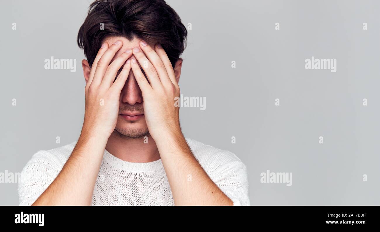 Studio Portrait Of Ashamed Young Man Covering Face With Hands Stock ...