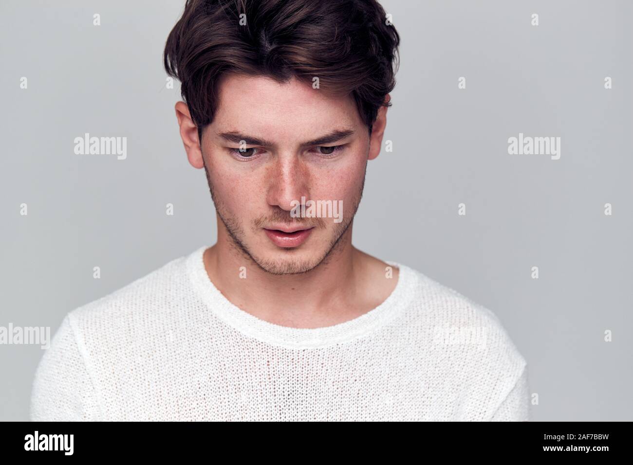 Studio Portrait Of Young Man With Guilty Expression Looking Down Stock ...