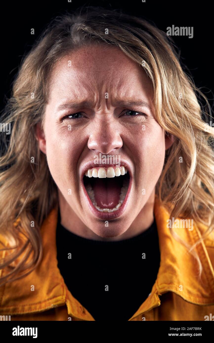 Studio Portrait Of Angry Woman Shouting At Camera Against Black ...