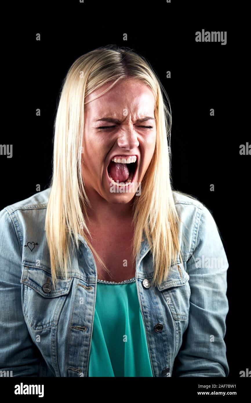 Studio Portrait Of Angry Woman Shouting At Camera Against Black ...