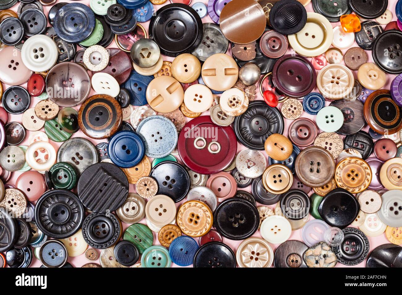 top view of pile of many different buttons close up on pink Stock Photo ...