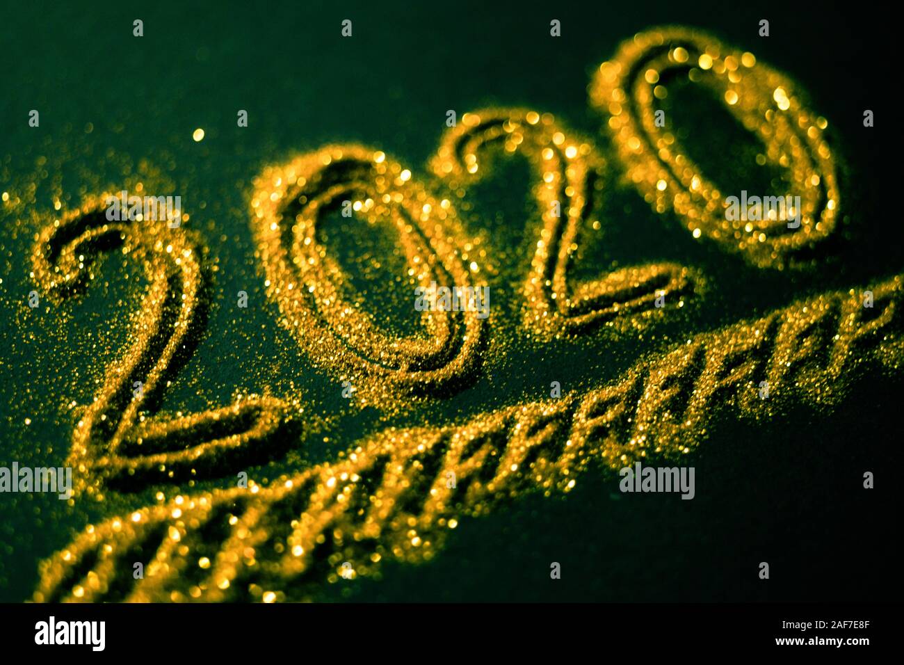 2020 number poured from gold glitters on a dark green background Stock ...