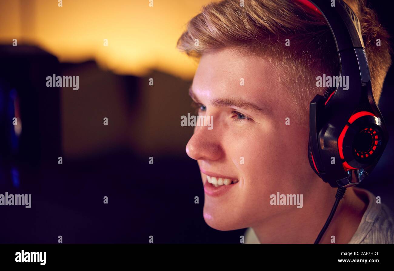 Teenage Boy Wearing Headset Gaming At Home Using Dual Computer Screens ...