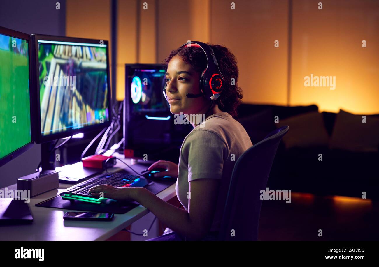 Teenage Girl Wearing Headset Gaming At Home Using Dual Computer Screens ...
