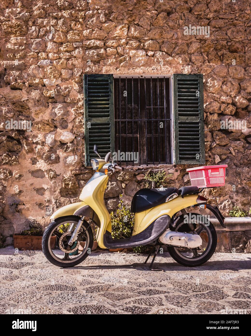 Old yellow motorcycle located beneath a typical Spanish window with old ...
