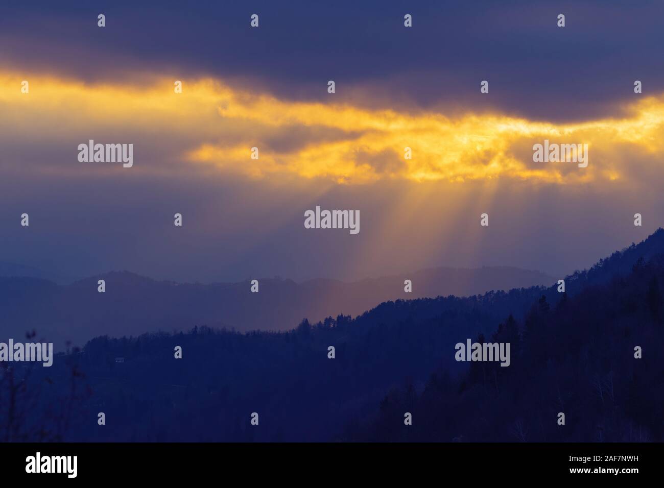 Rays of sunlight shining through clouds over dark landscape in the ...