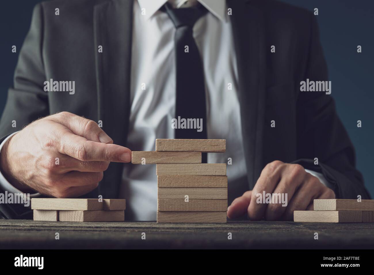 Businessman pushing a peg in a stack of them in a conceptual image of ...