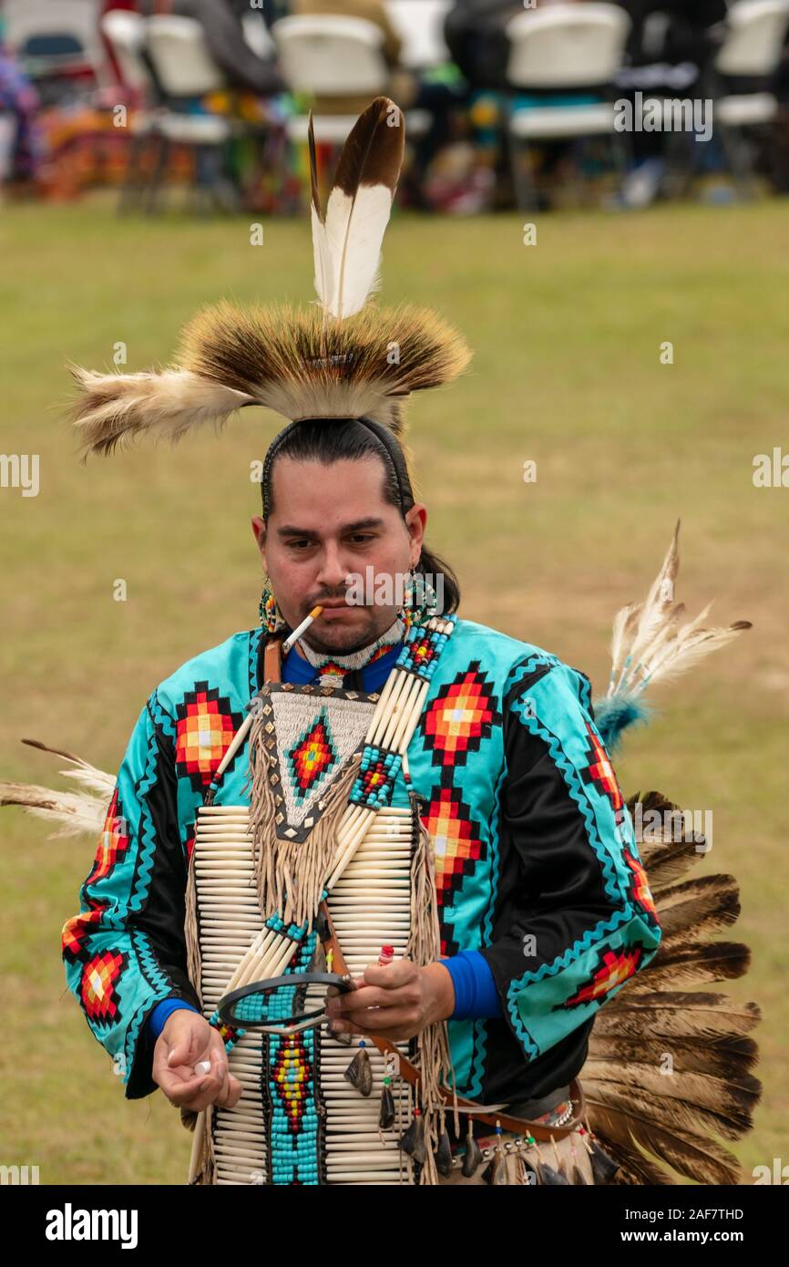A man with a porcupine quill headdress smokes a cigarette at the Poarch ...