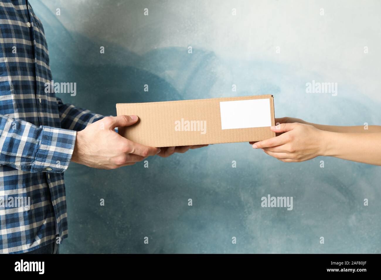 Woman receiving boxes from delivery man against blue background, blank ...