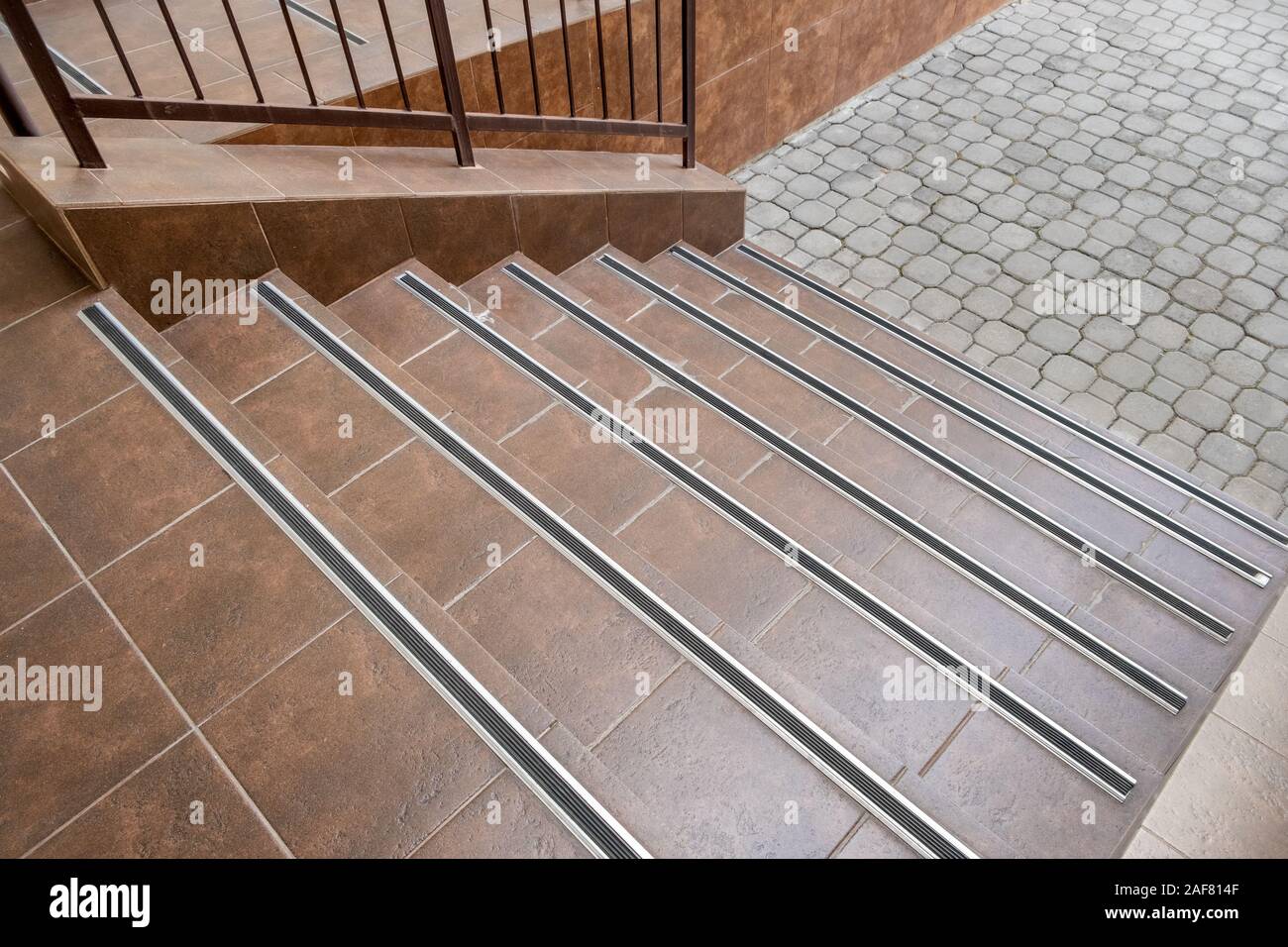 Concrete entrance stairs covered with ceramic tiles with metal railings ...