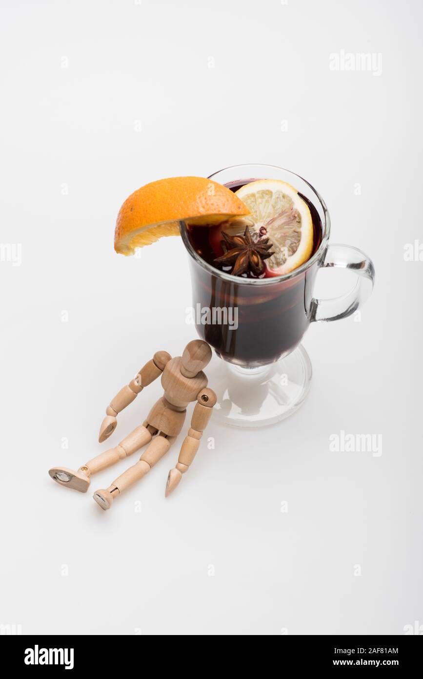 Humanlike toy sitting drunk near glass of wine. Wine with lemon slices ...