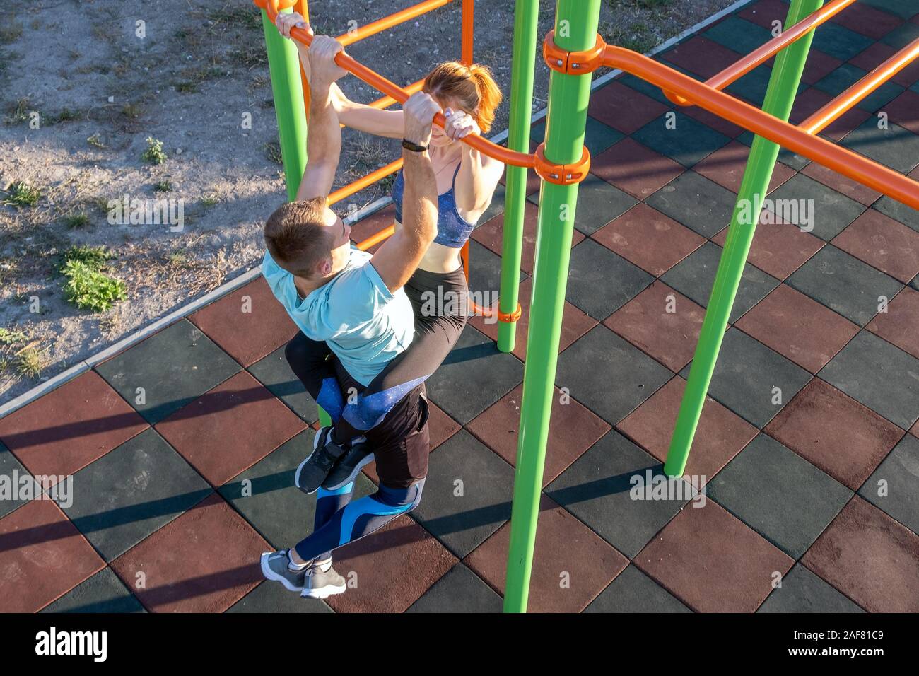 Young fit athlete working out at outdoor gym making dipping pull ups ...