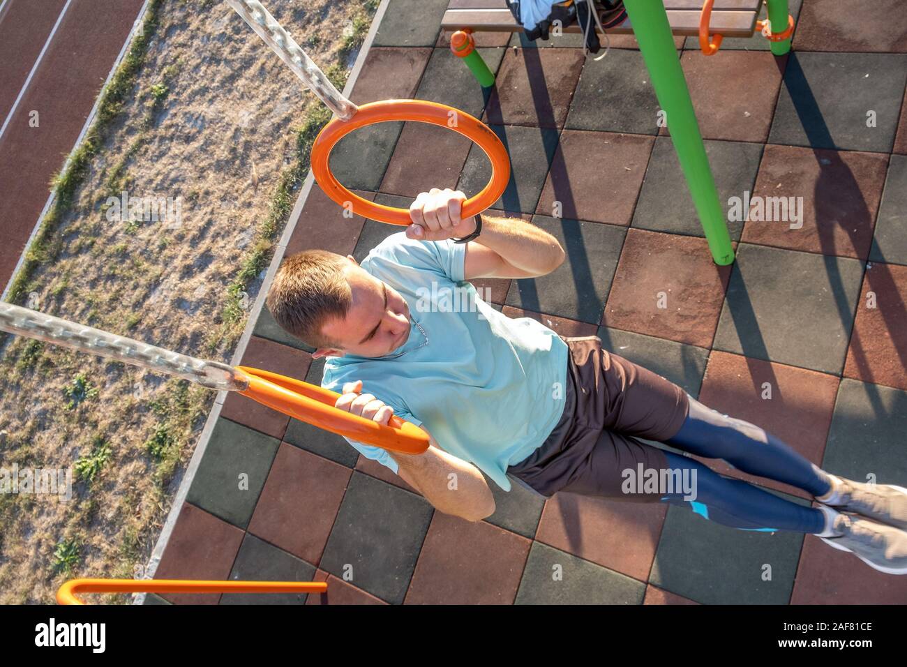 Young fit athlete working out at outdoor gym making dipping pull ups ...