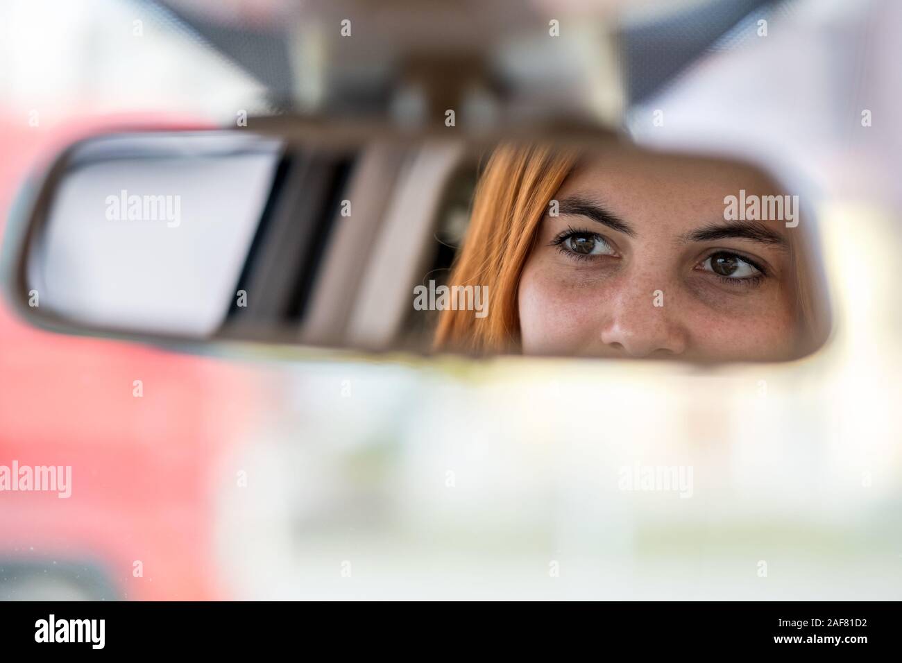 Young woman driver checking rear view mirror looking backwards while ...