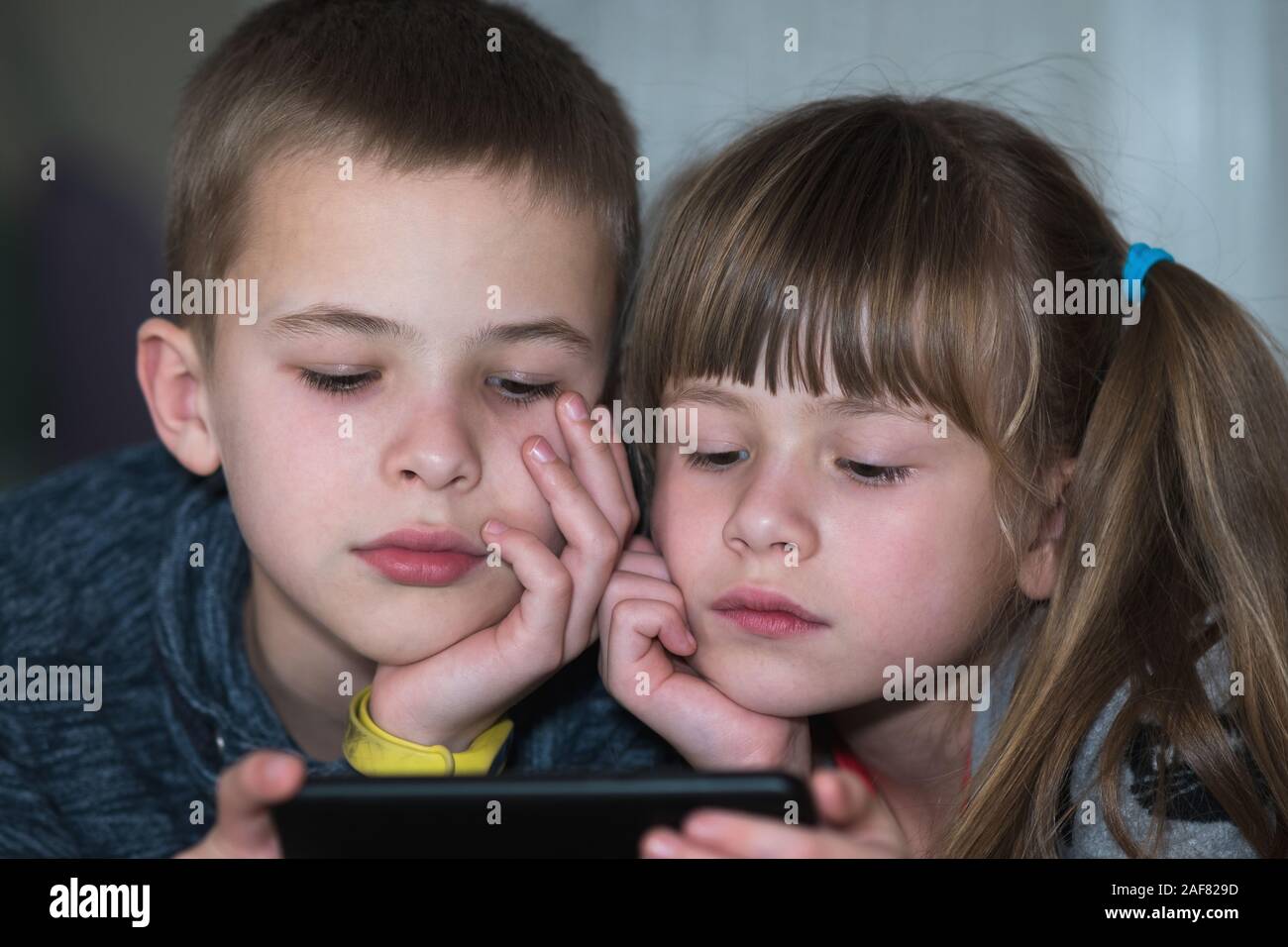 Two children brother and sister watching video on smartphone screen ...