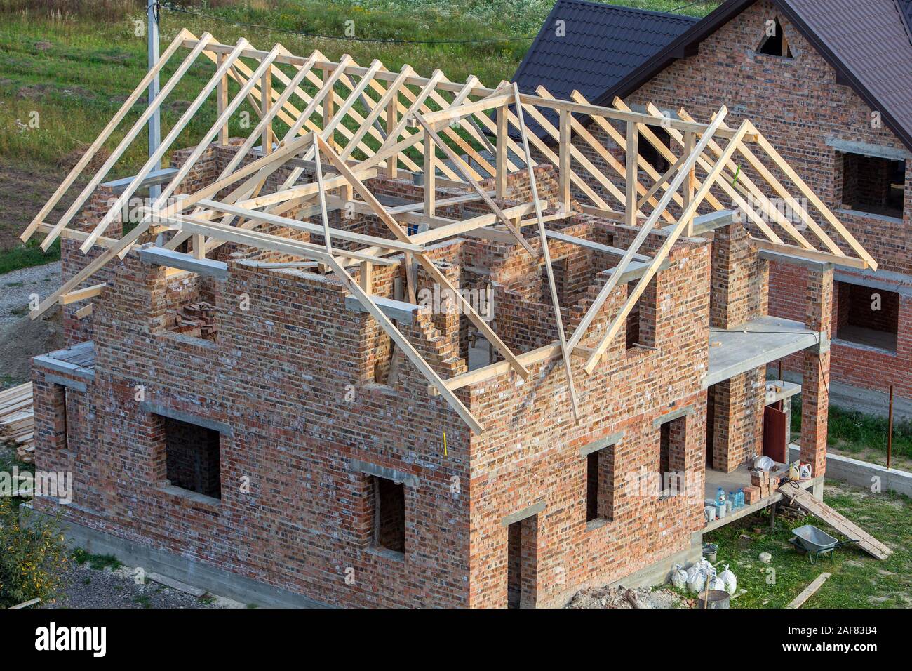 Unfinished brick house with wooden roof structure under construction ...