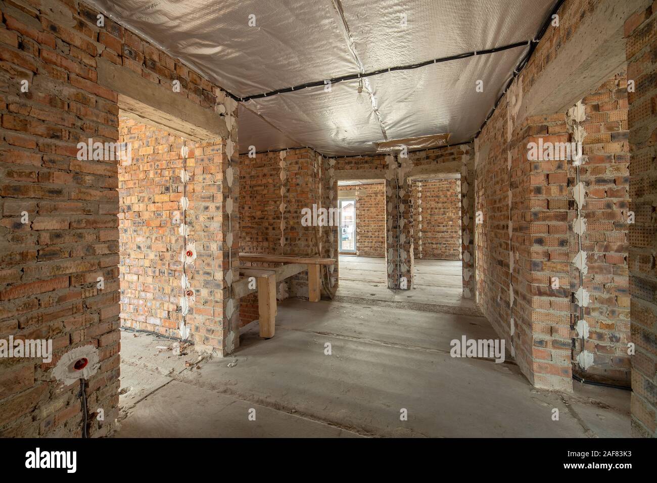 Interior of unfinished brick house with concrete floor and bare walls ...