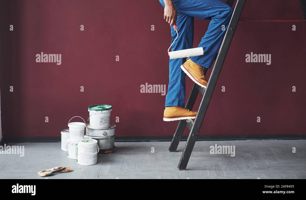 Walking up the ladder. Young african american worker in the blue ...