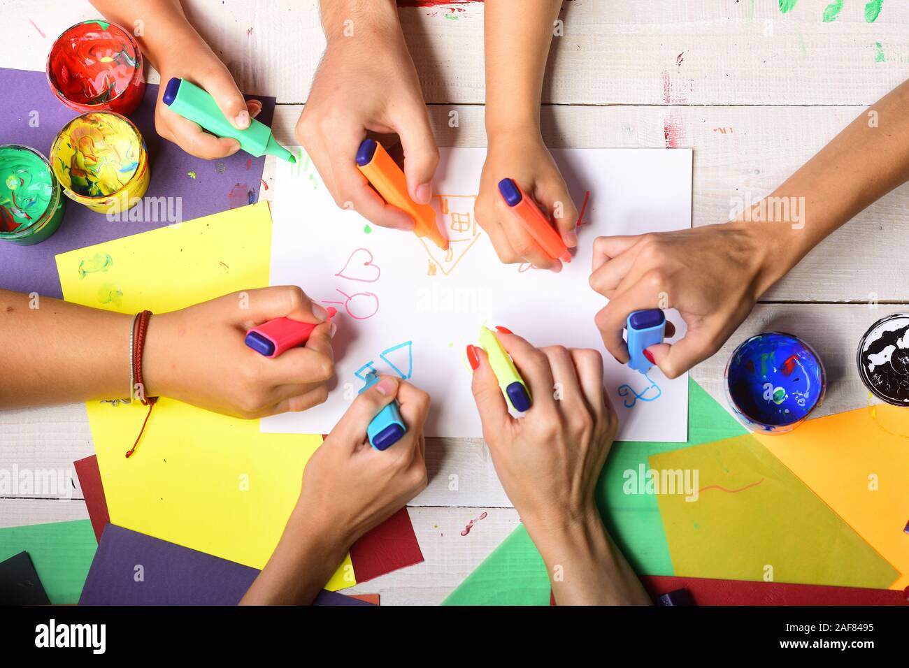 Markers in male and female hands draw on white paper with cute drawings ...
