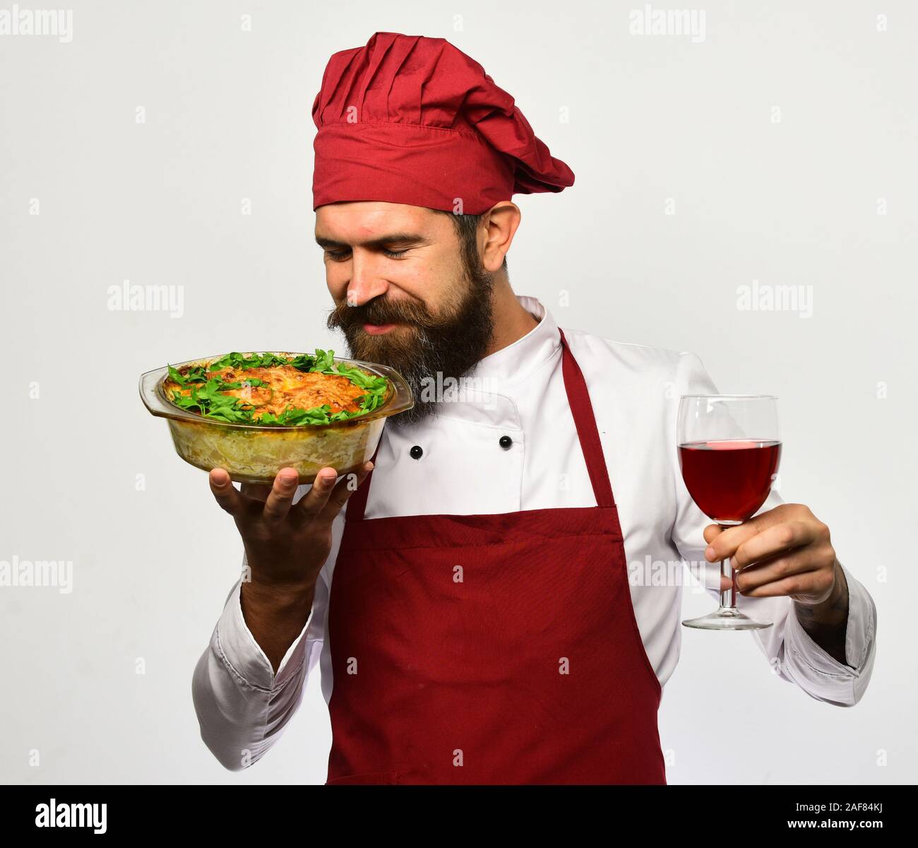 Chef holds bowl with potato casserole and glass of alcohol. Cook with ...