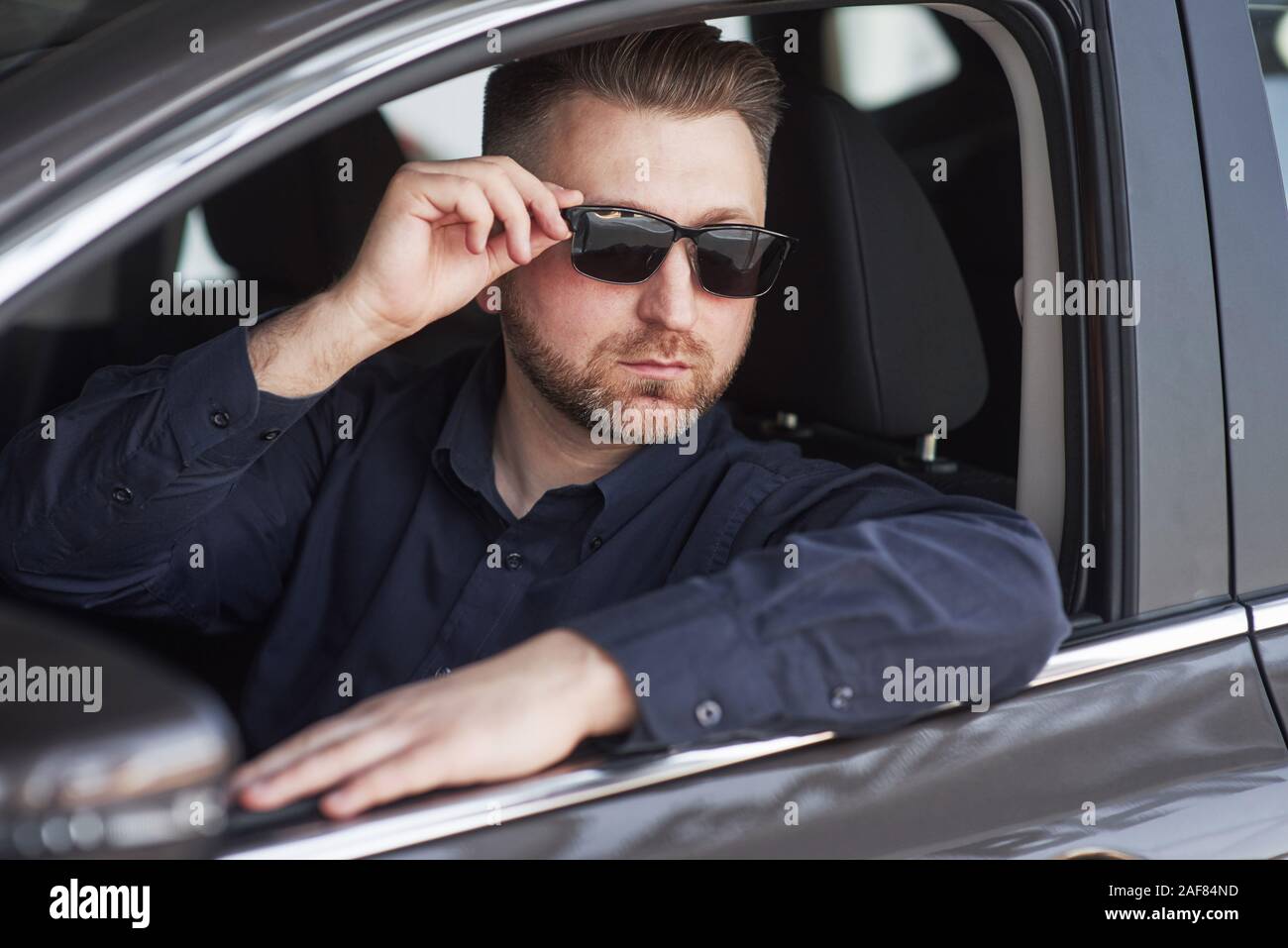 Stylish look. Man in official clothes trying his new car in automobile ...