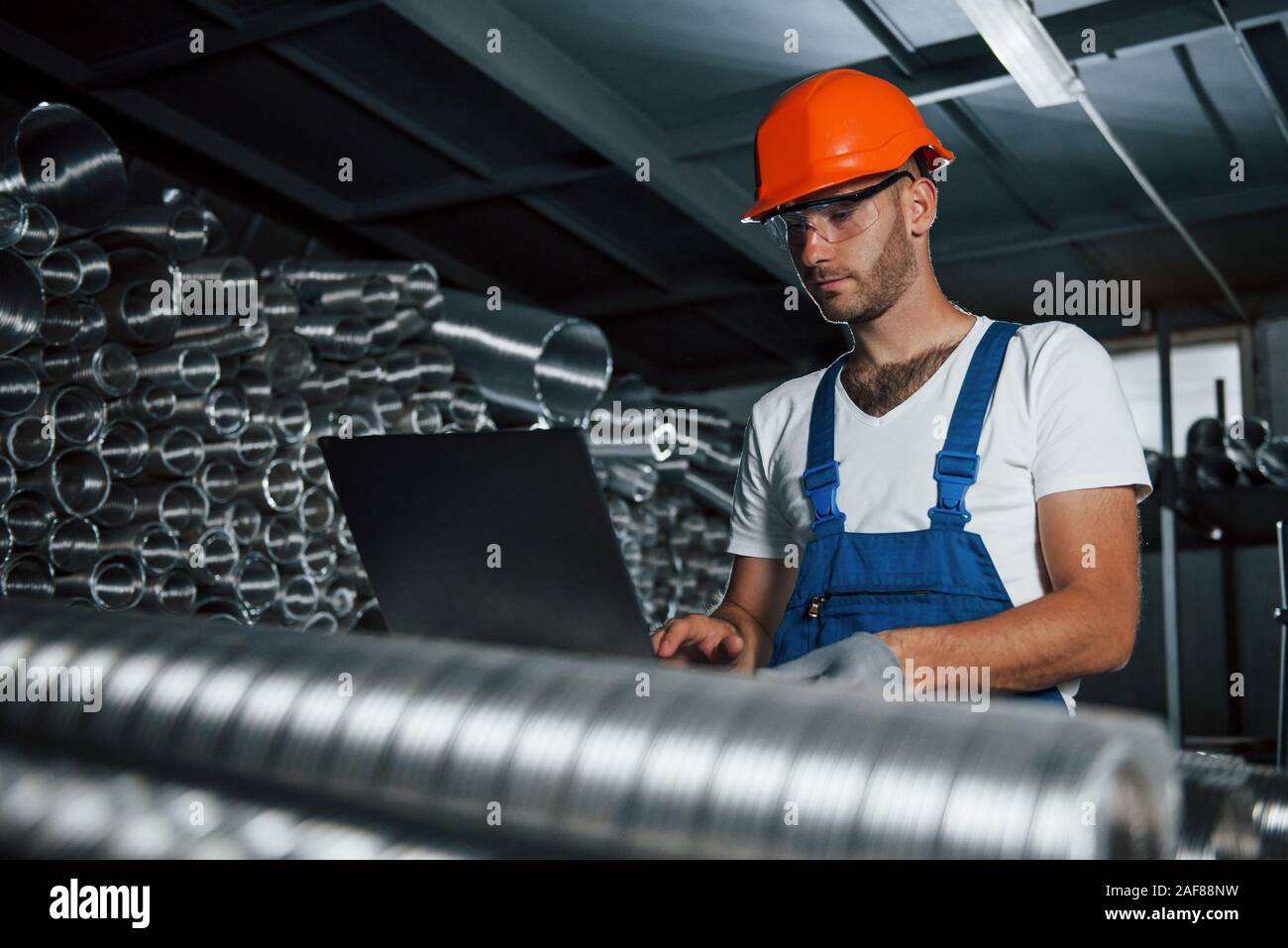 Production of metal pipes. Man in uniform works on the production ...