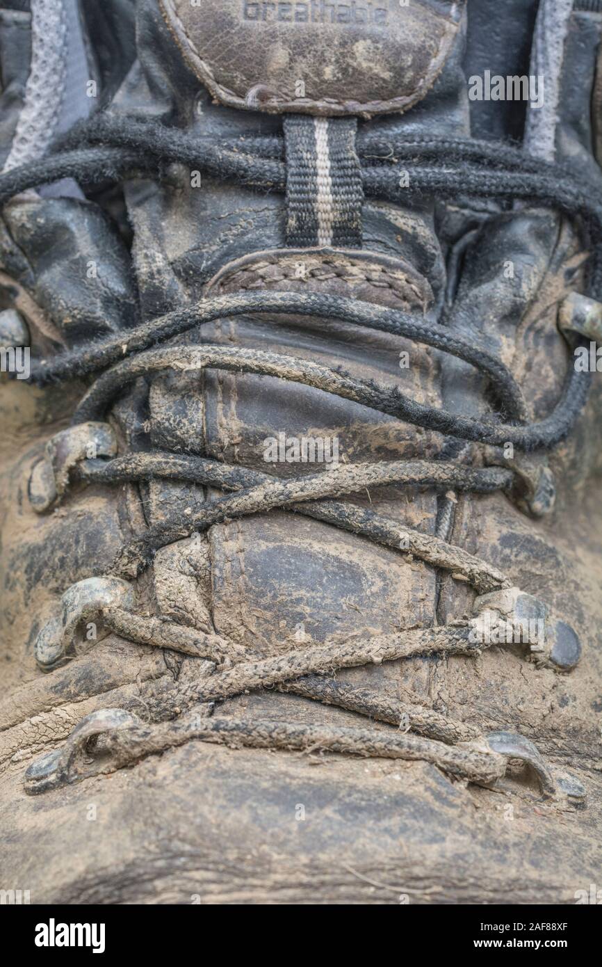 Close-up shot of muddy bootlaces and eyelets on a pair of tired old ...
