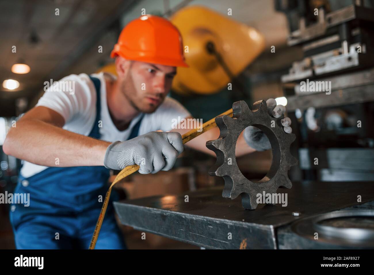 Measures the width. Man in uniform works on the production. Industrial ...