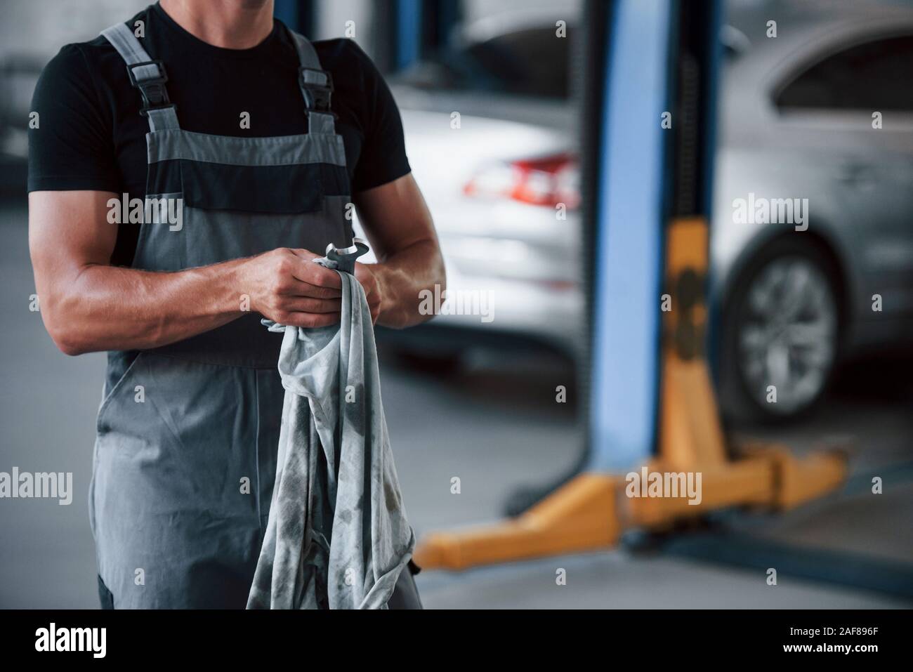 Preparing for the job. Man in black shirt and grey uniform stands in ...