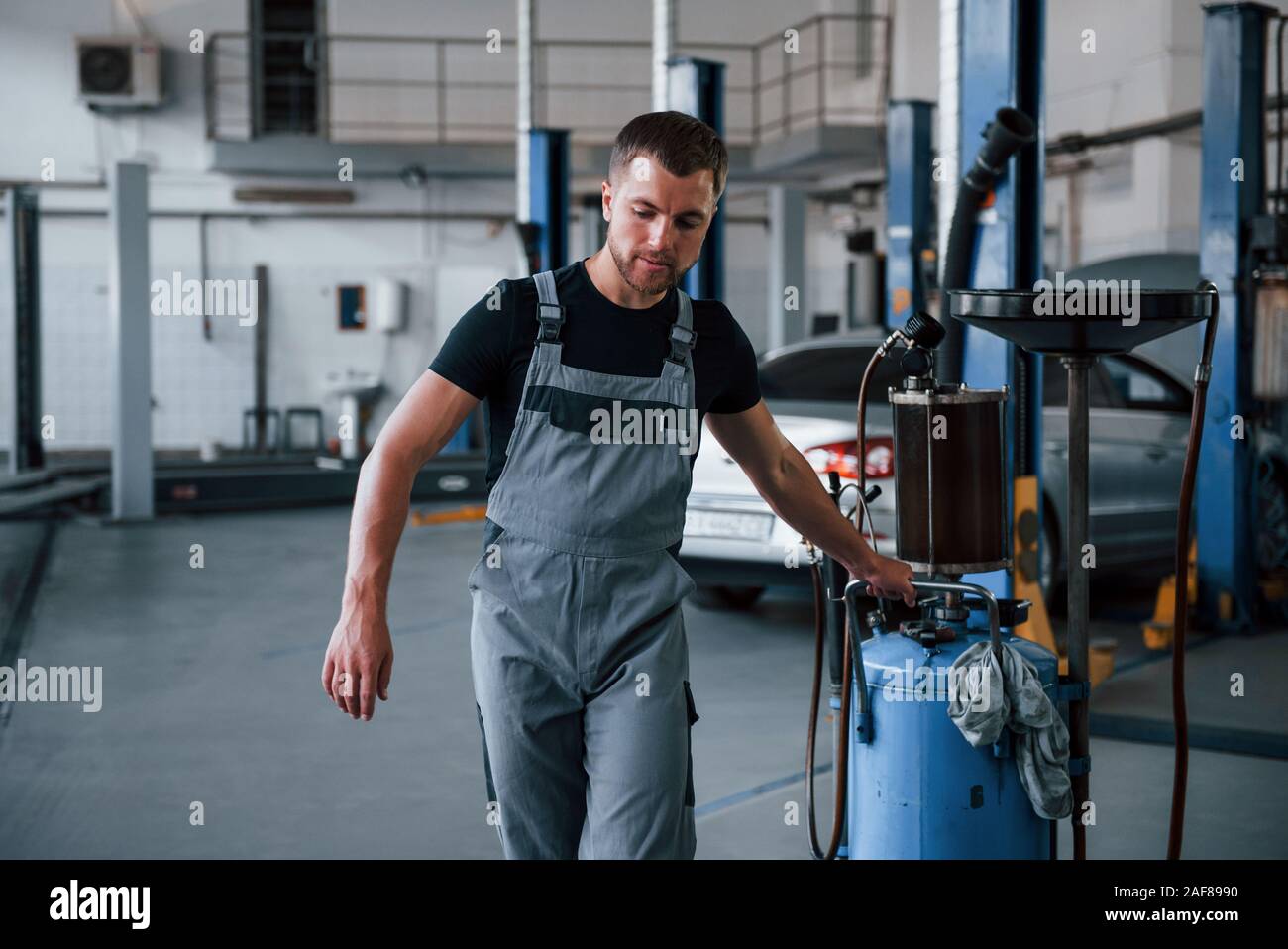 Concentrated at work. Male mechanic use special device to repair broken ...