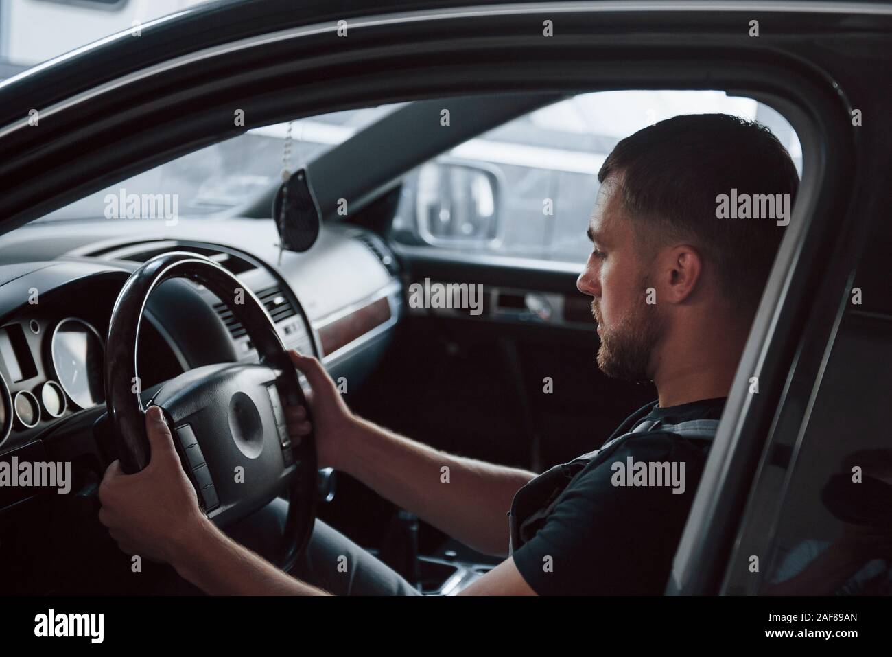 Guy test brand new car in the garage. Black colored interior. Hands on ...