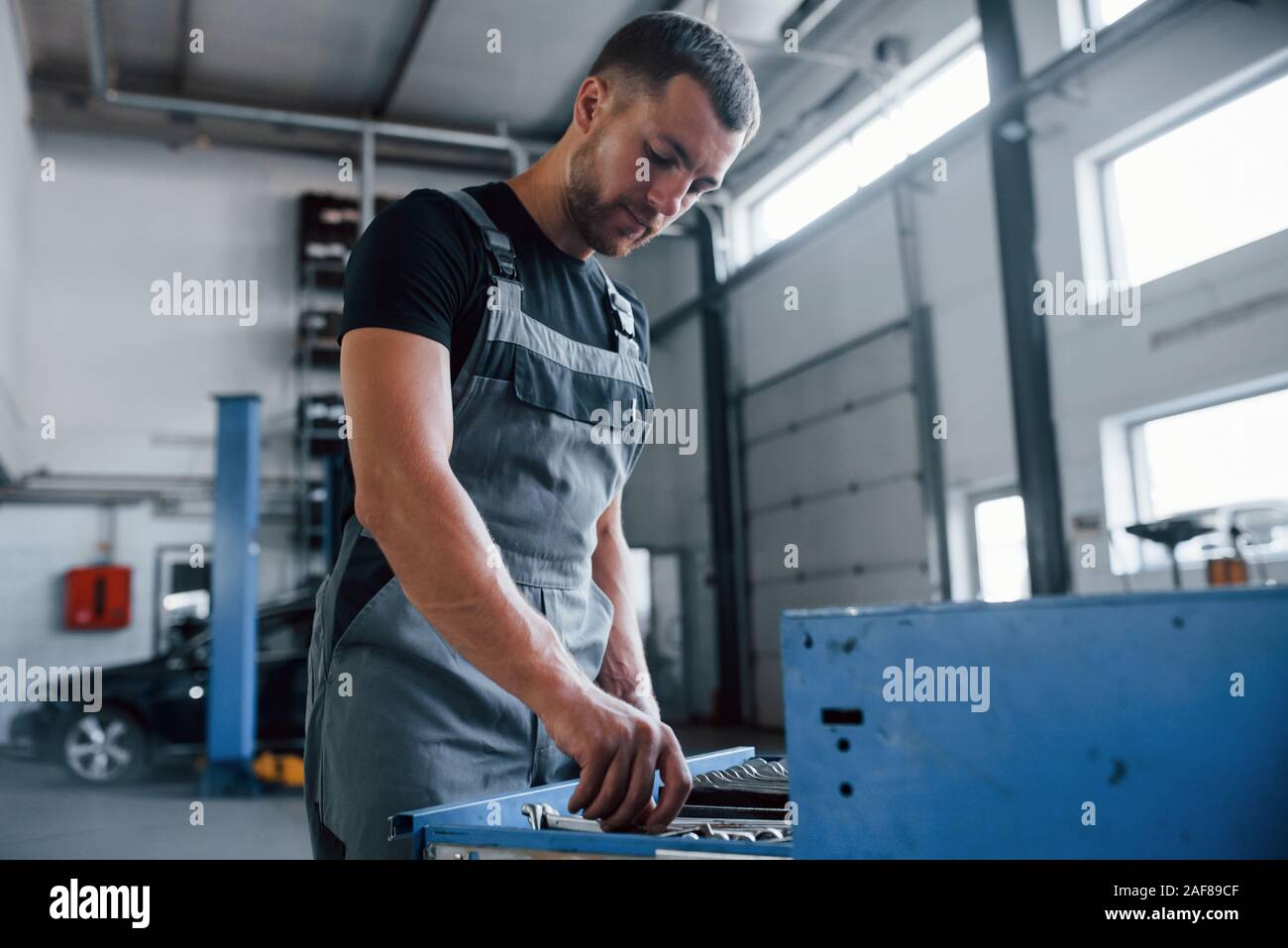 Blue colored drawer. Male mechanic use different tools to repair broken ...
