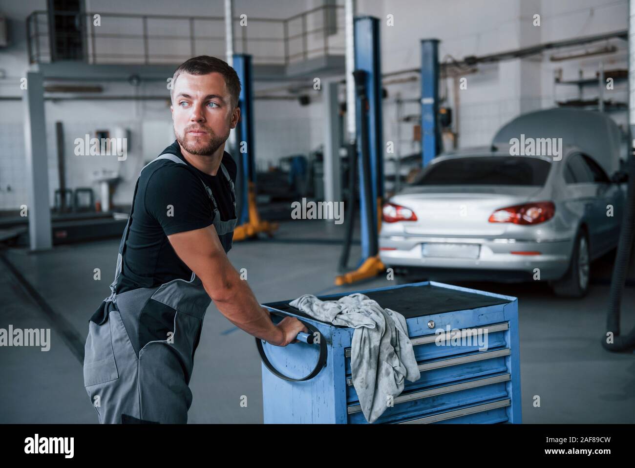 Moves to the car. Male mechanic use different tools to repair broken ...