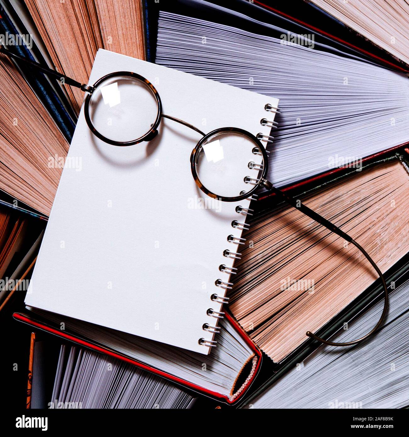 Many multicolored thick open books stand on a dark background. On the ...