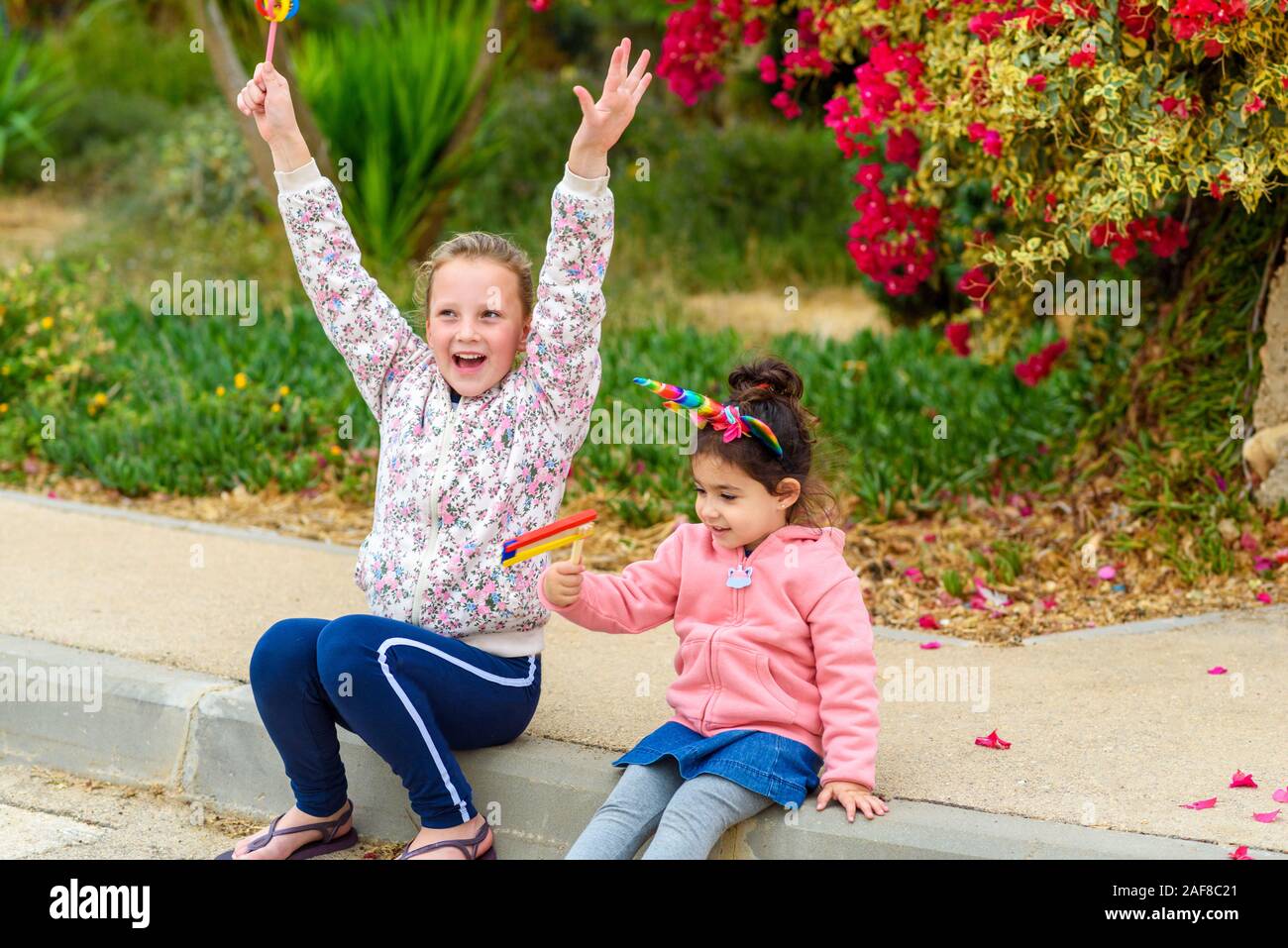 Funny teenager girl holding wooden grogger and happy toddler girl ...
