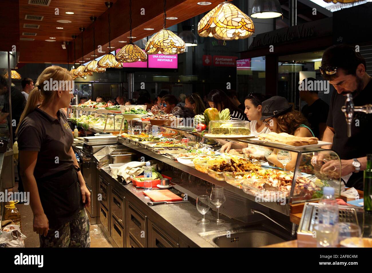 People seated and working staff in a snack bar in the Mercado de La ...