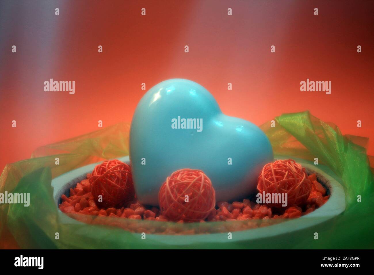 white ceramic heart in wooden bowl with orange decoration and green ...