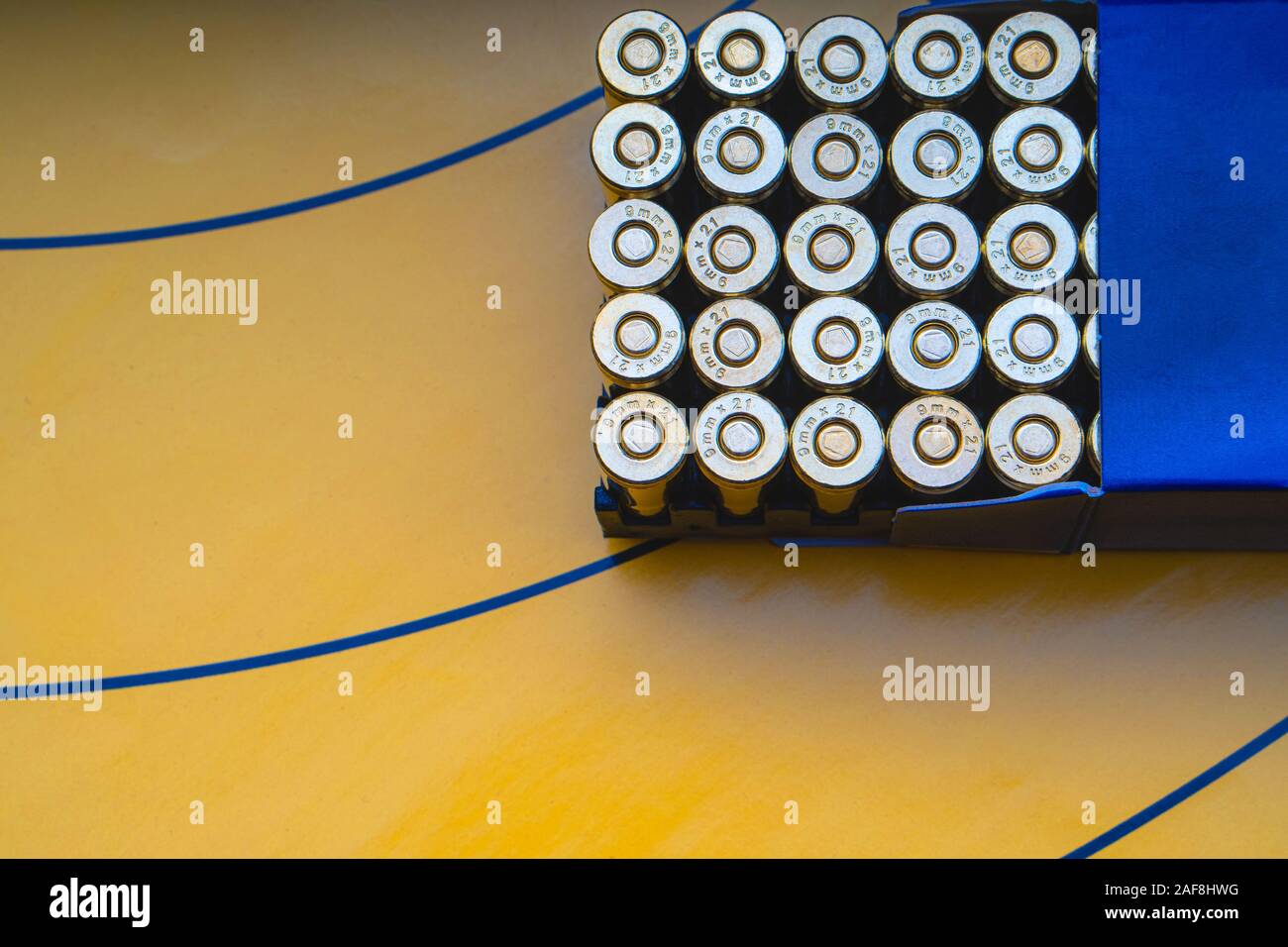 Cartridges in a blue box on a background of a yellow target. 9 mm ...