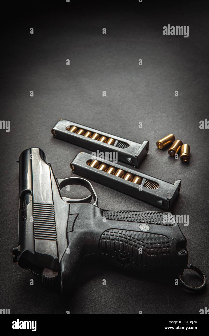 A modern black pistol and ammunition on dark metal background. Weapons ...
