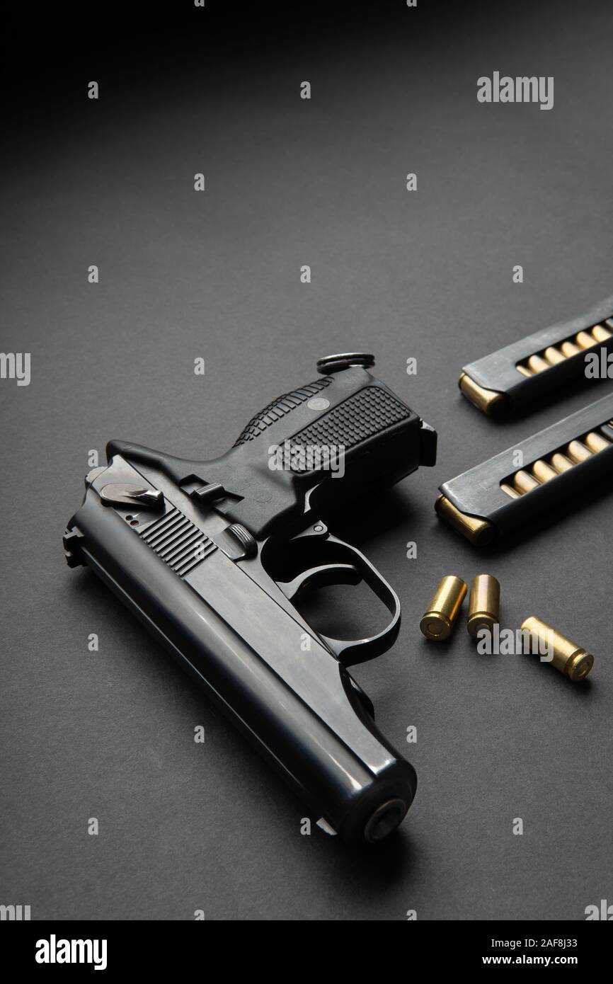 A modern black pistol and ammunition on dark background. Weapons for ...