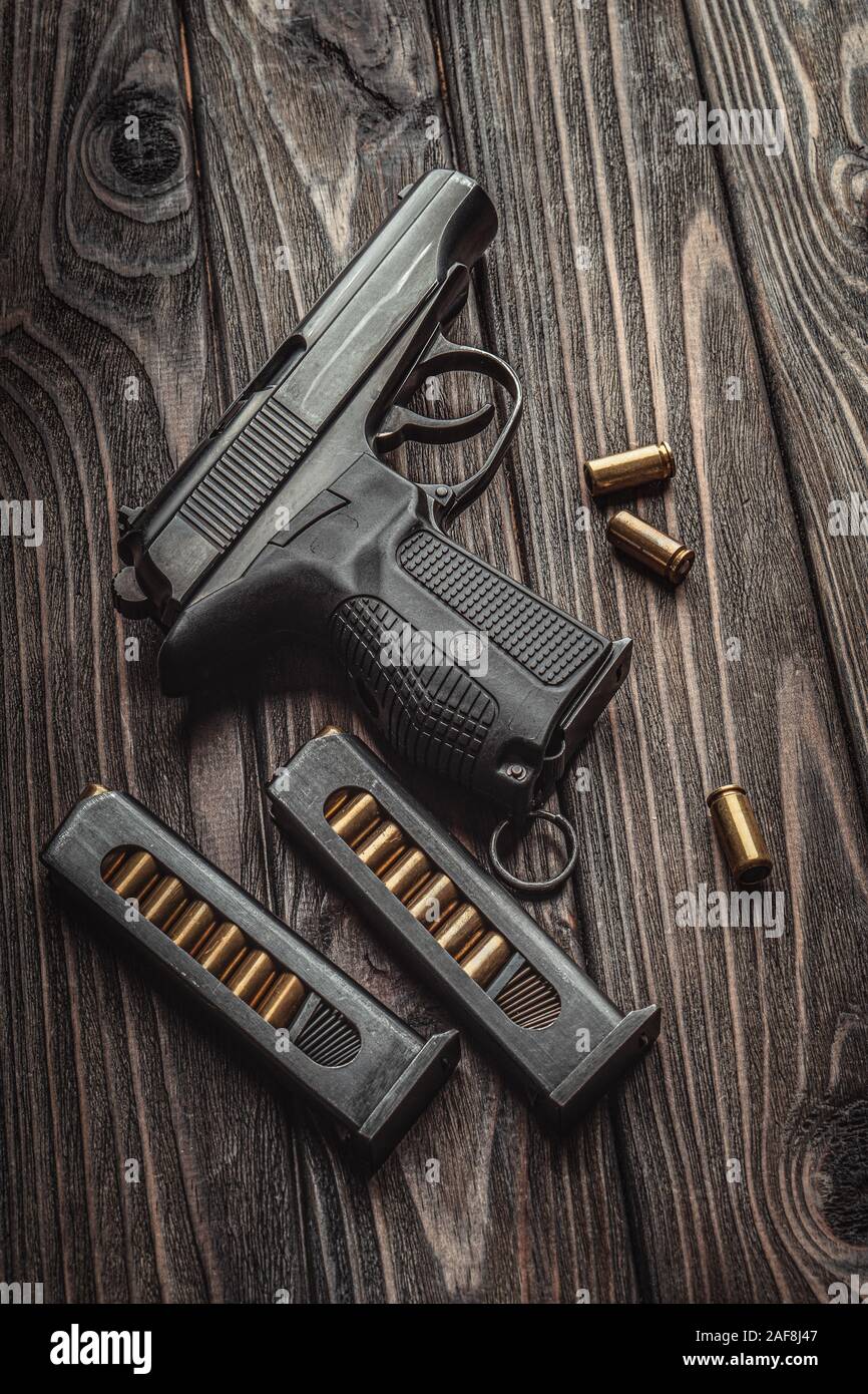 A modern black pistol and ammunition on dark wooden background. Weapons ...