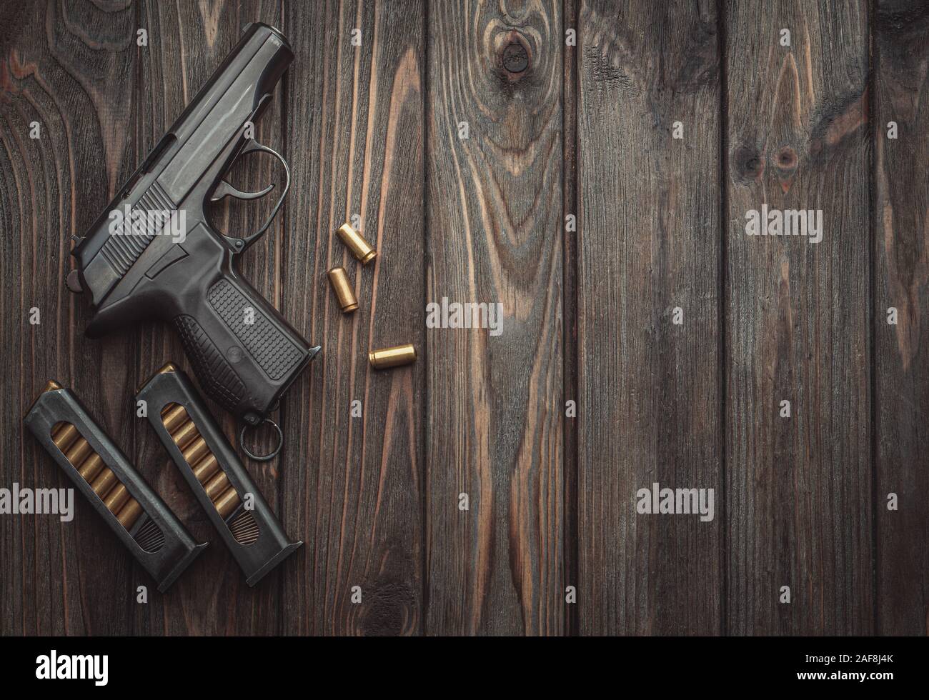 A modern black pistol and ammunition on dark wooden background. Weapons ...